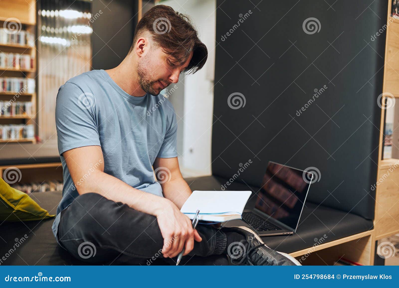 Student Learning in University Library. Young Man Reading His Notes ...