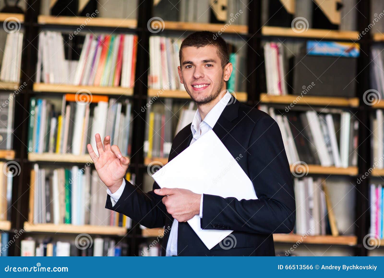 Student in Library. Handsome Young Man Holding Books and Smiling while ...