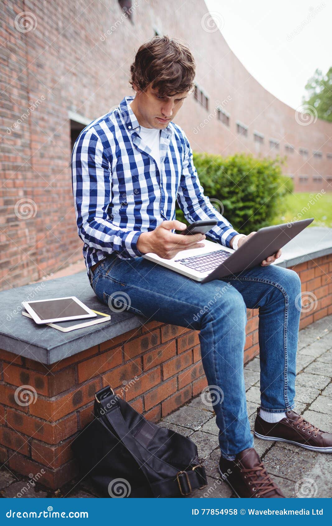 Student Sitting with Laptop Using Mobile Phone in Campus Stock Photo ...