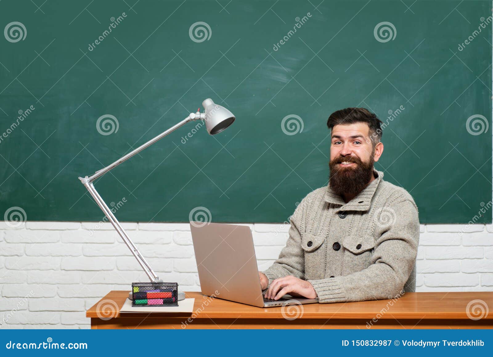 Student Sitting at Table and Writing on Notebook. Teacher Teaches a ...