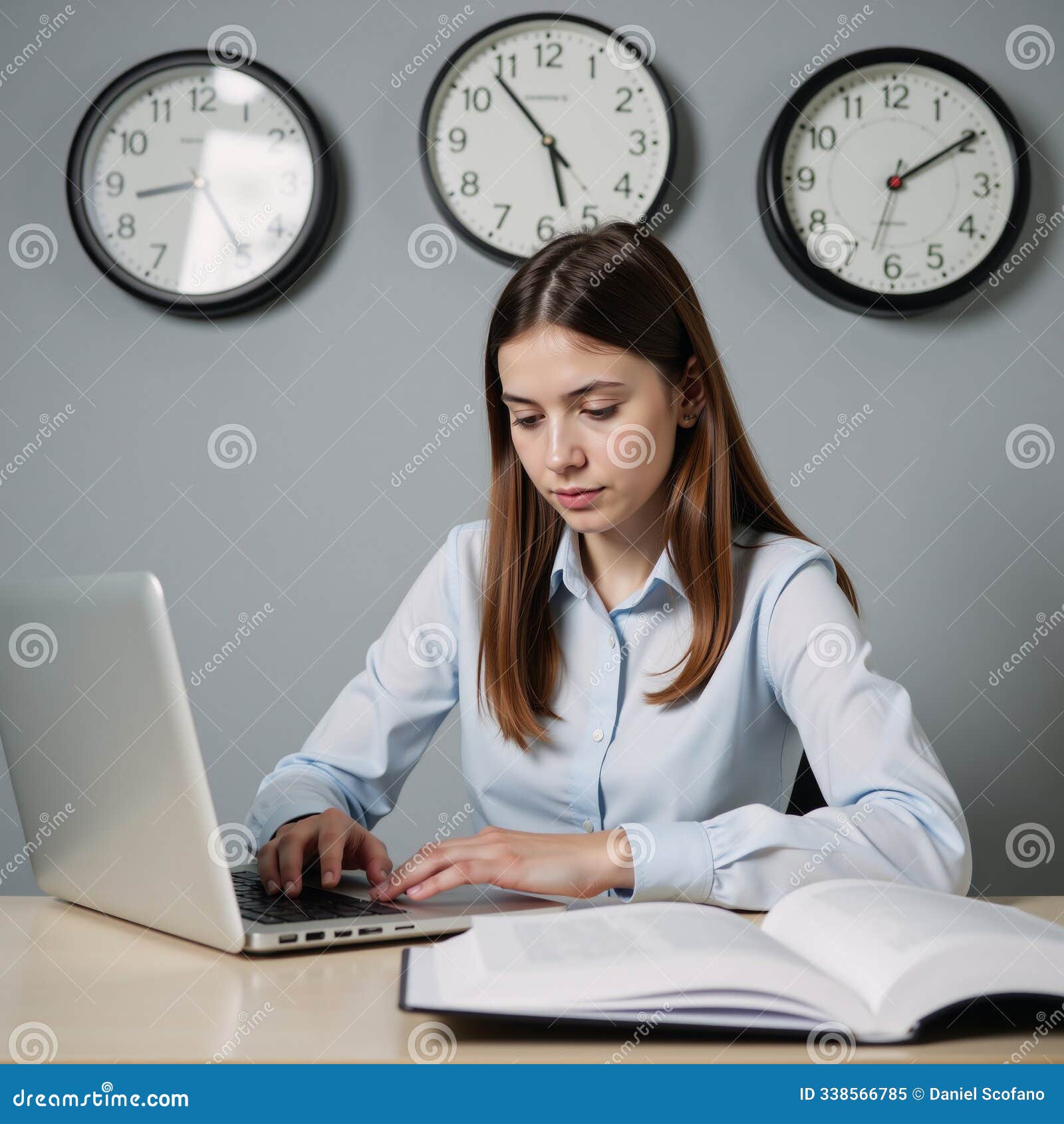 Student Studying at Cluttered Desk with Laptops and Multiple Clocks ...