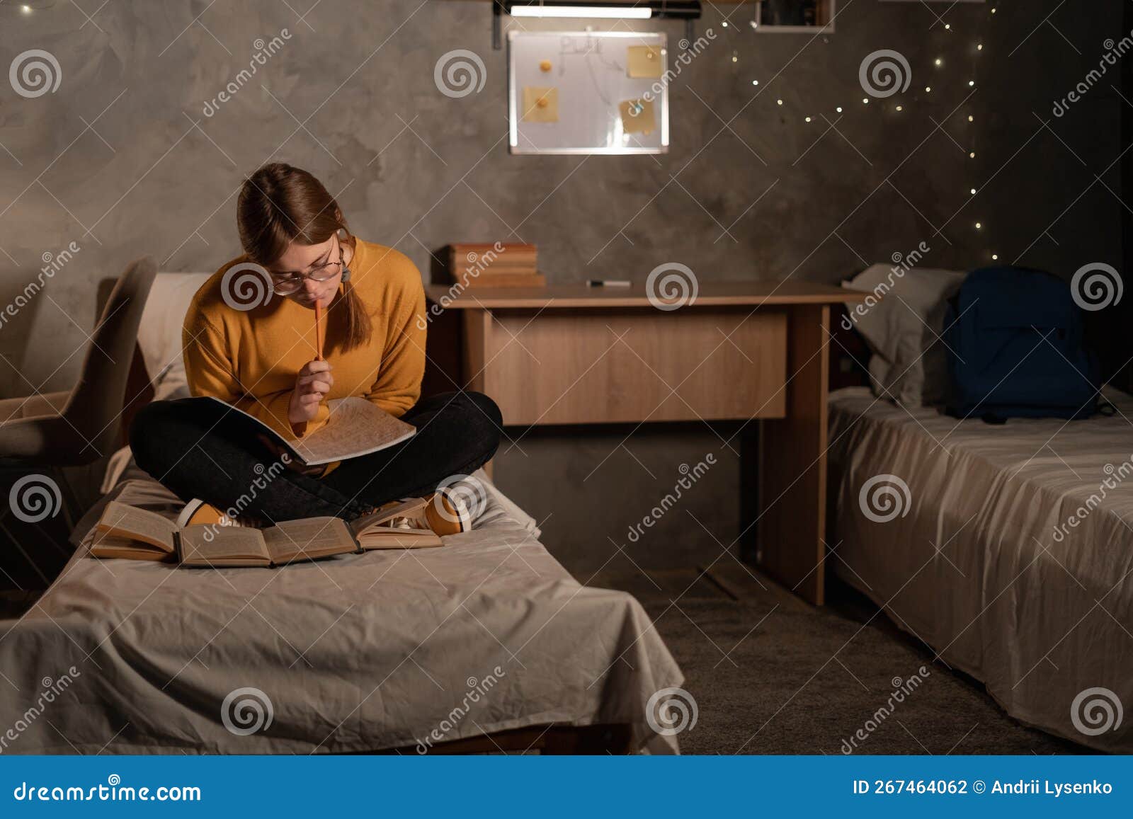 Student Studying in the Dormitory Room Sitting on the Bed in the ...