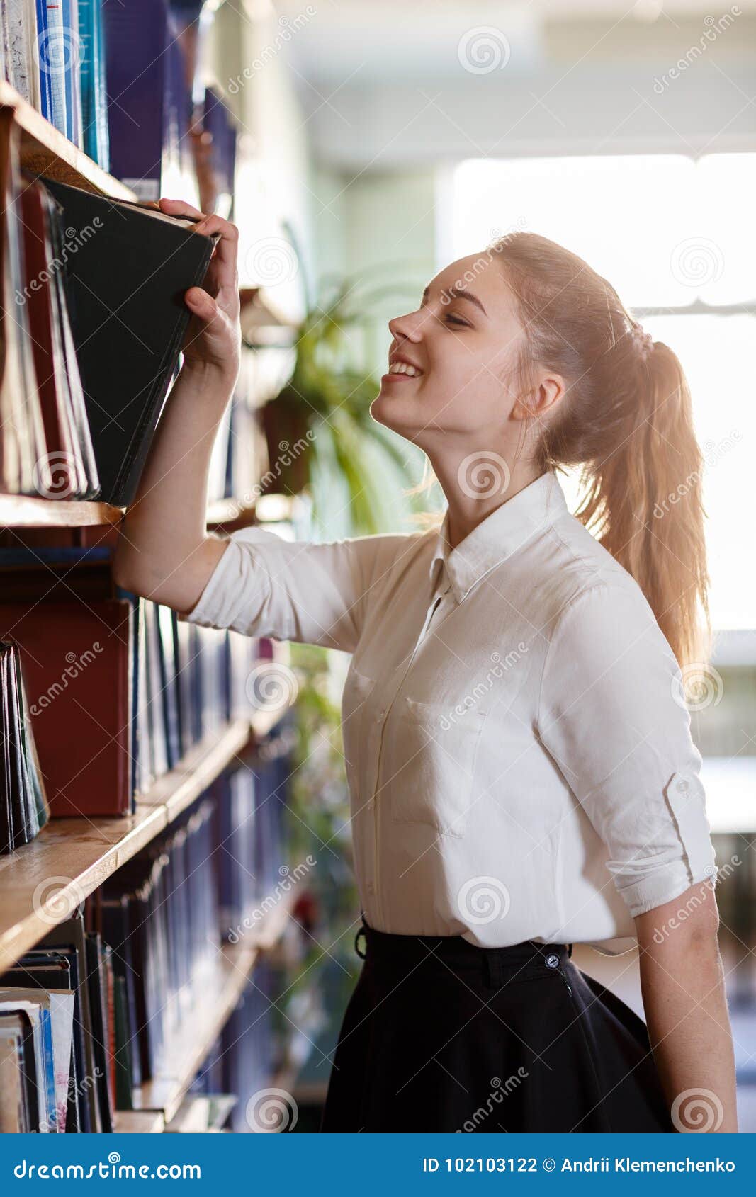 A Student Taking a Book from a Shelf in the Library. Stock Photo ...