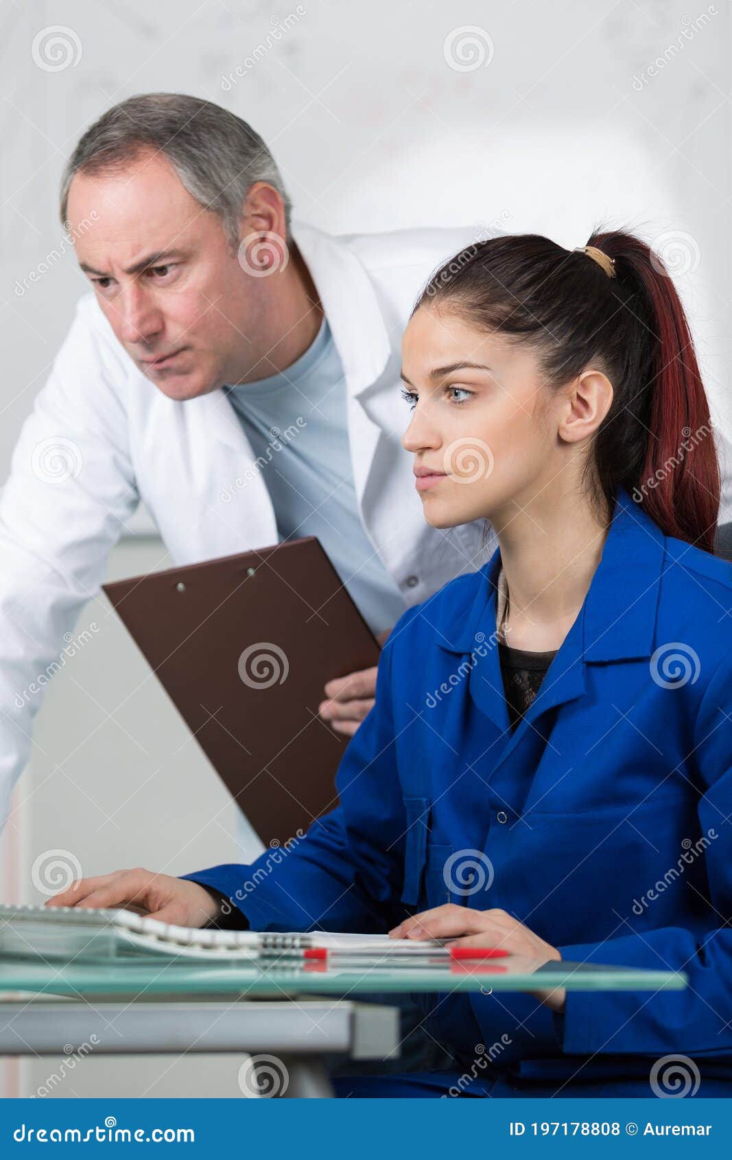 Student Using Computer Teacher with Clipboard Looking Over Shoulder ...