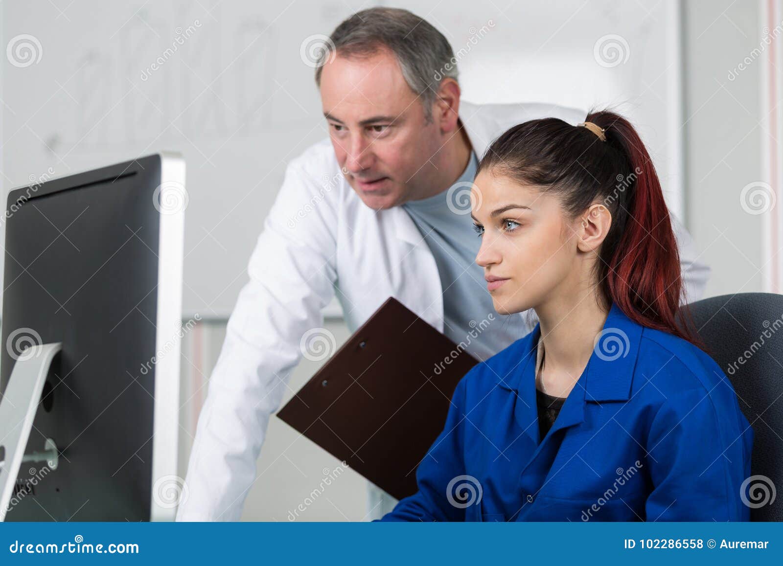 Student Using Computer Teacher with Clipboard Looking Over Shoulder ...