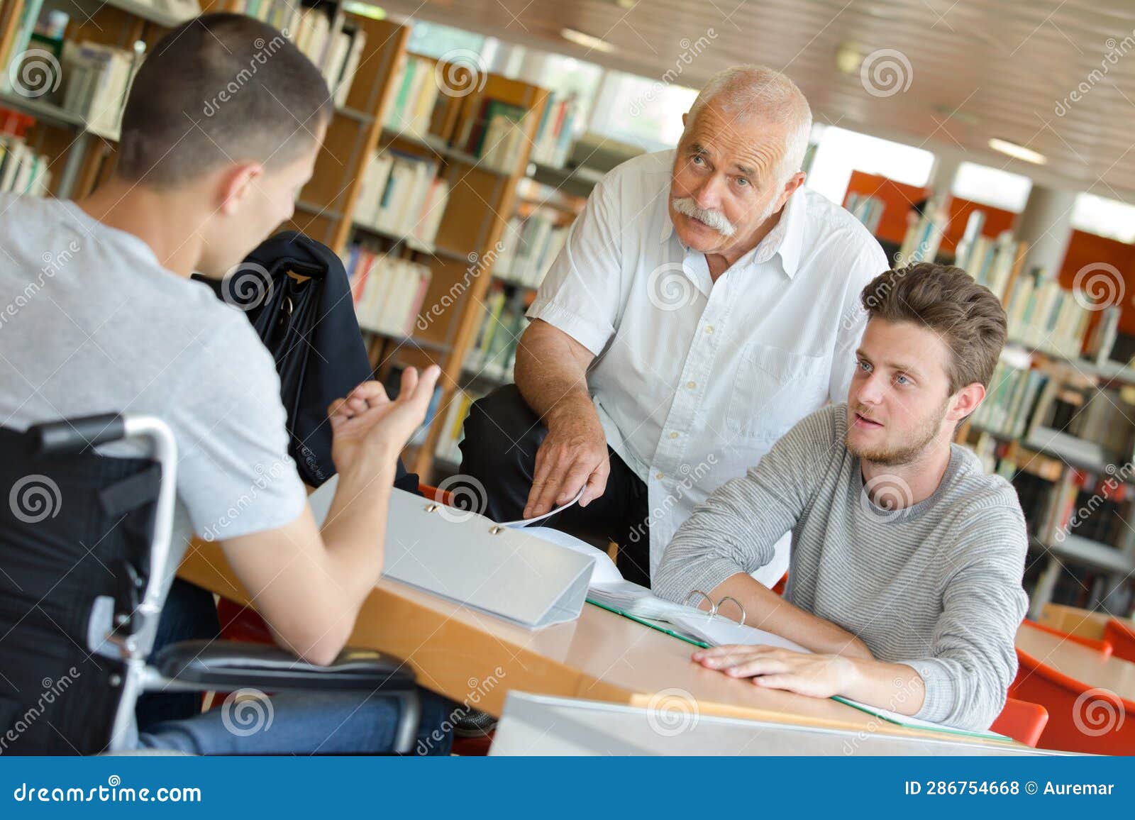 Student in Wheelchair Talking with Classmate in Library Stock Photo ...