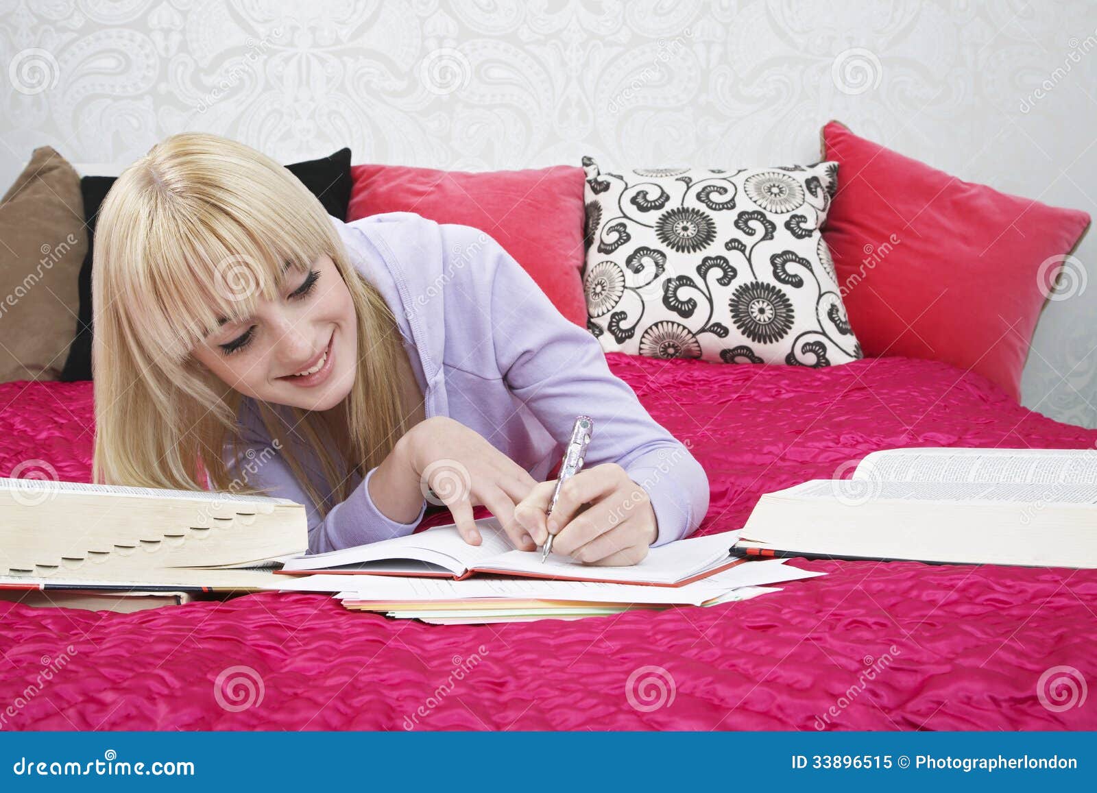 Student Writing in Book while Smiling on Bed Stock Image - Image of ...