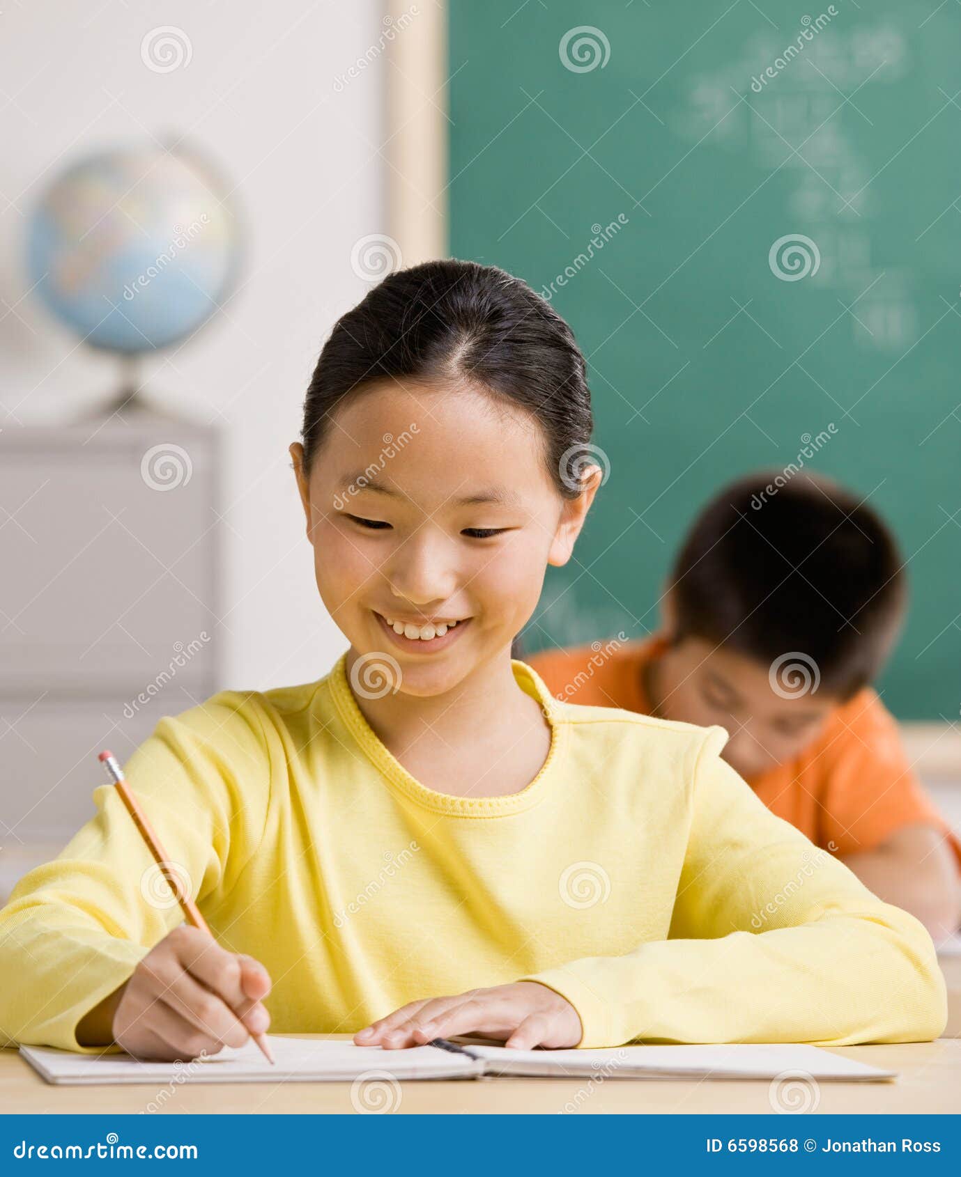 Student Writing in Notebook in School Classroom Stock Photo - Image of ...