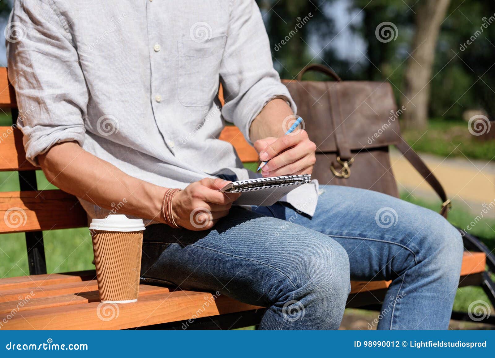 Student Writing in Notebook while Sitting on Bench in Park Stock Photo ...