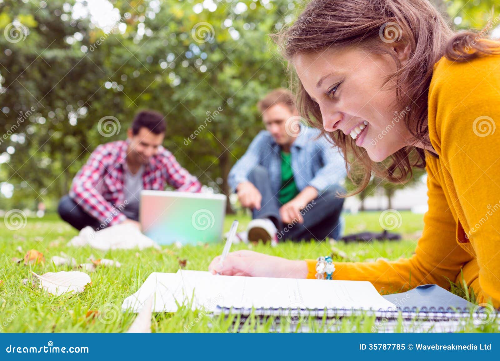 Student Writing Notes with Two Using Laptop in Park Stock Image - Image ...