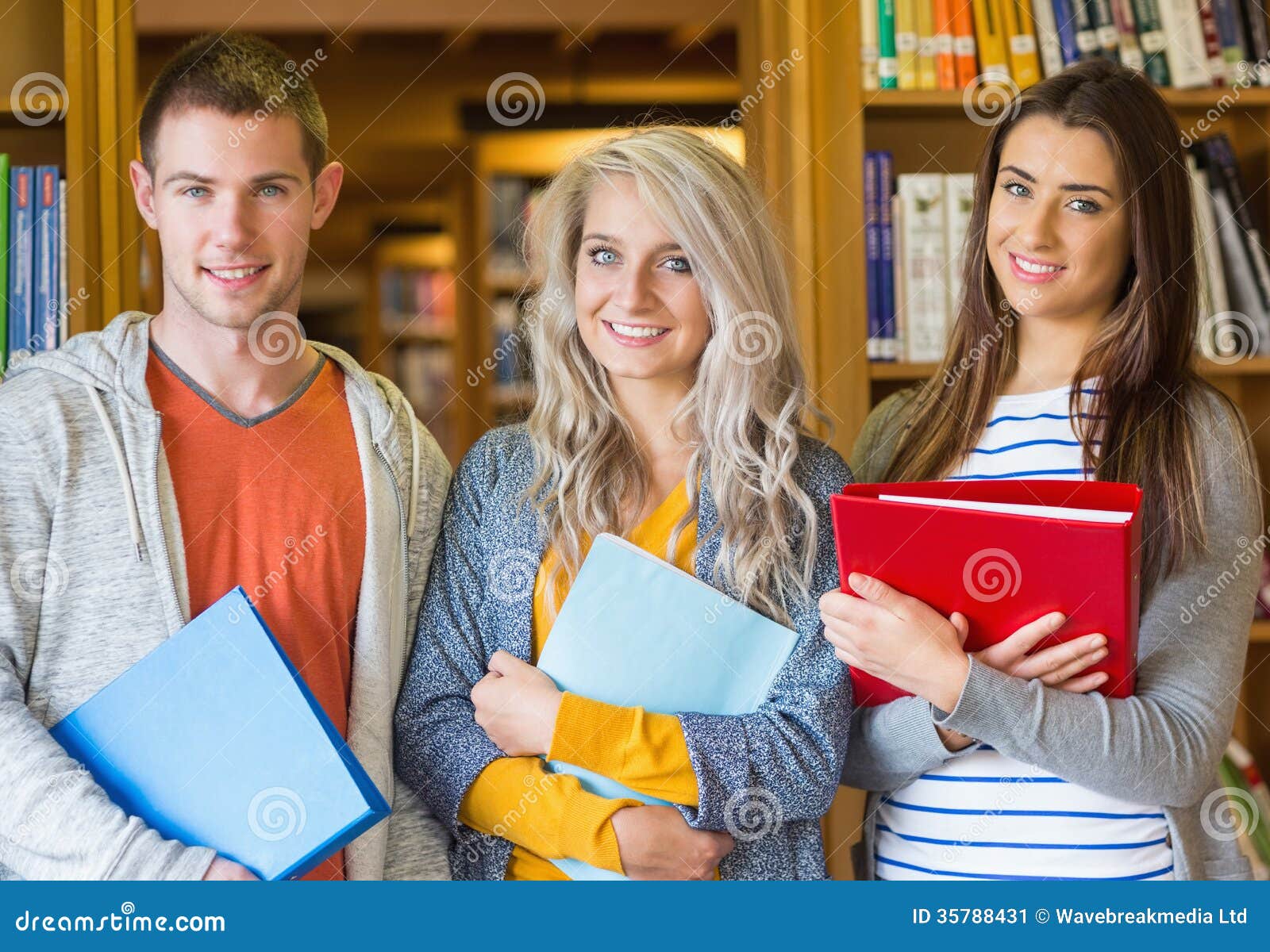 Students with Folders Standing Against Bookshelf in Library Stock Image ...