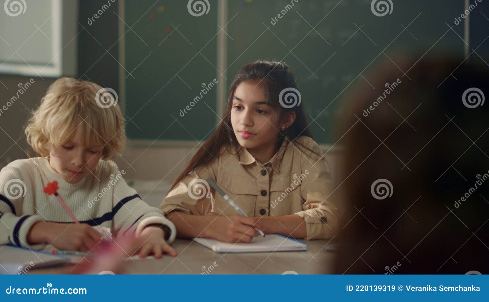 Students Learning at Round Table in School. Pupils Writing Text in ...