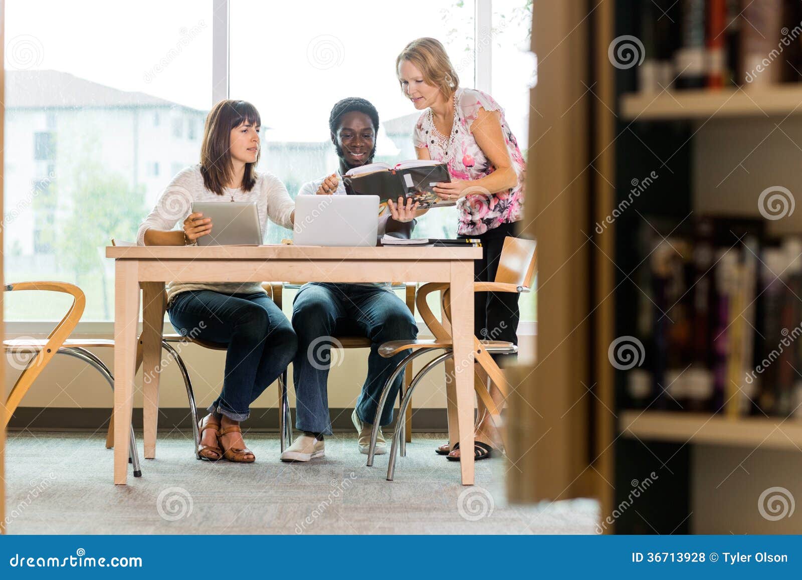 Students and Librarian Looking at Book in Library Stock Photo - Image ...