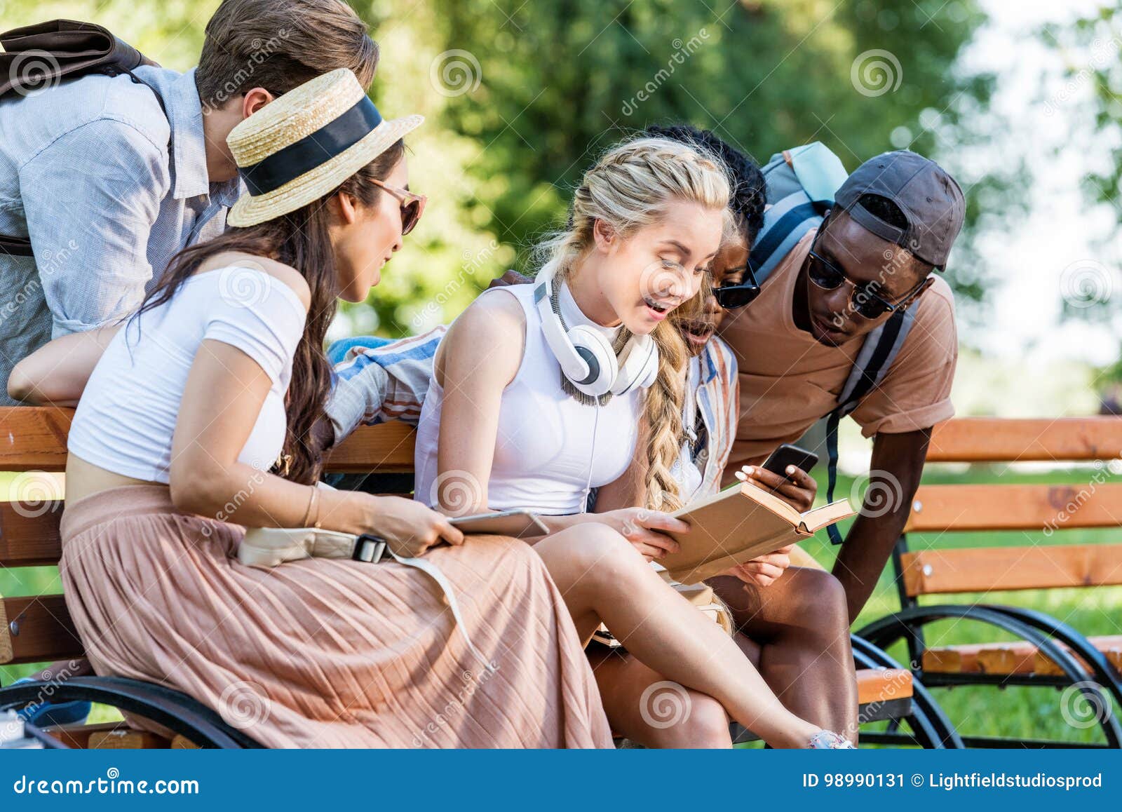 Students Reading Book while Sitting on Bench Together in Park Stock ...