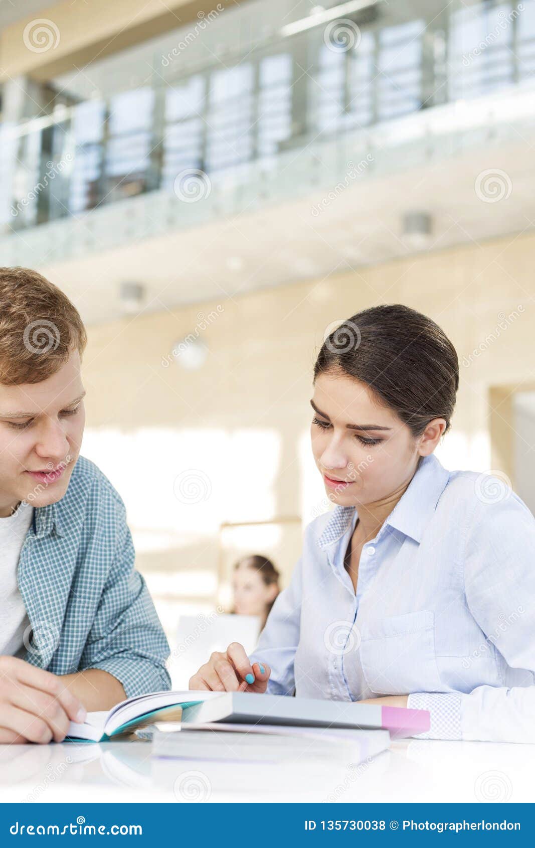Friends Discussing Over Book while Sitting Together at Table in ...