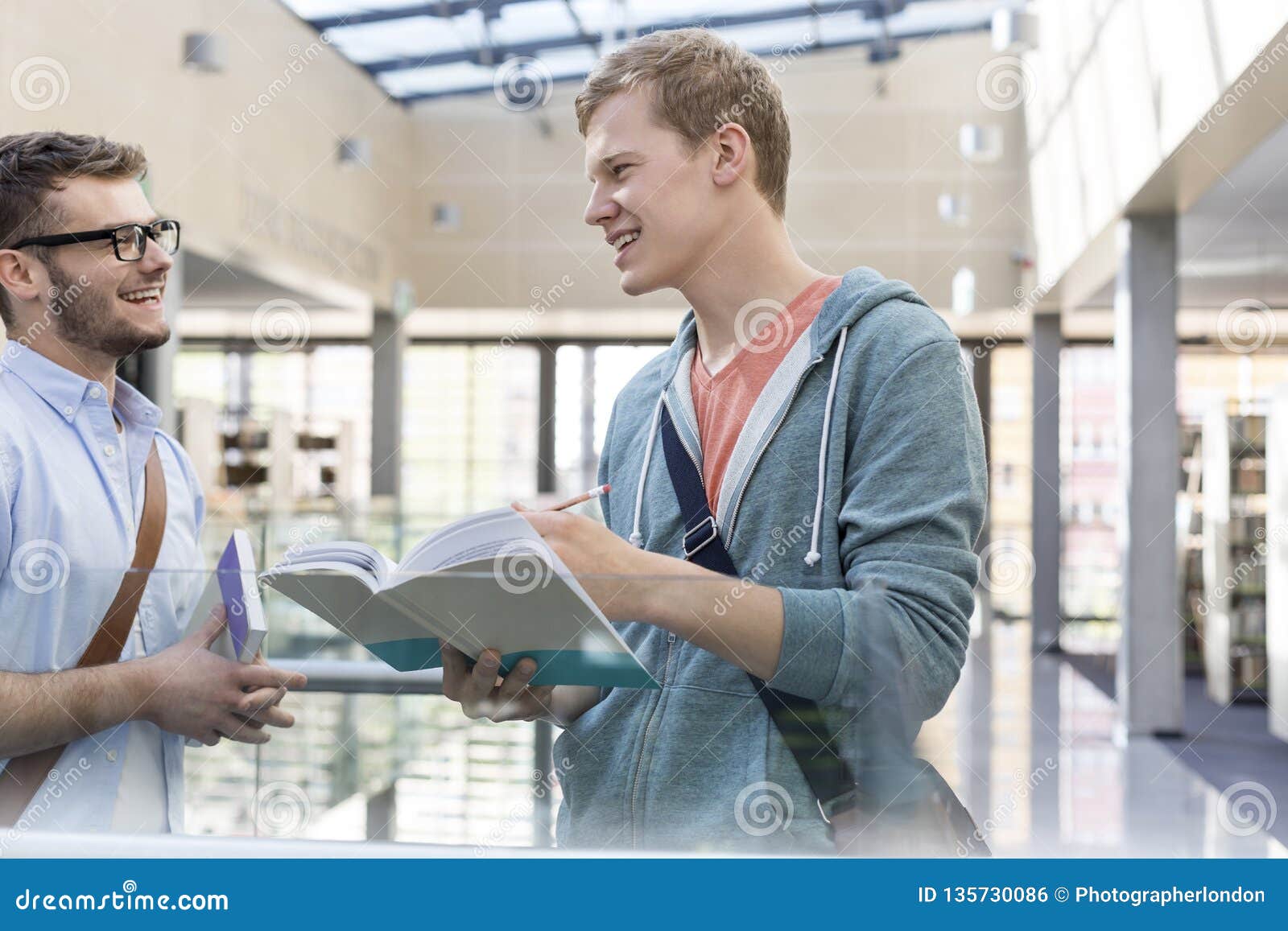 Happy Friends Talking while Reading Books at University Corridor Stock ...