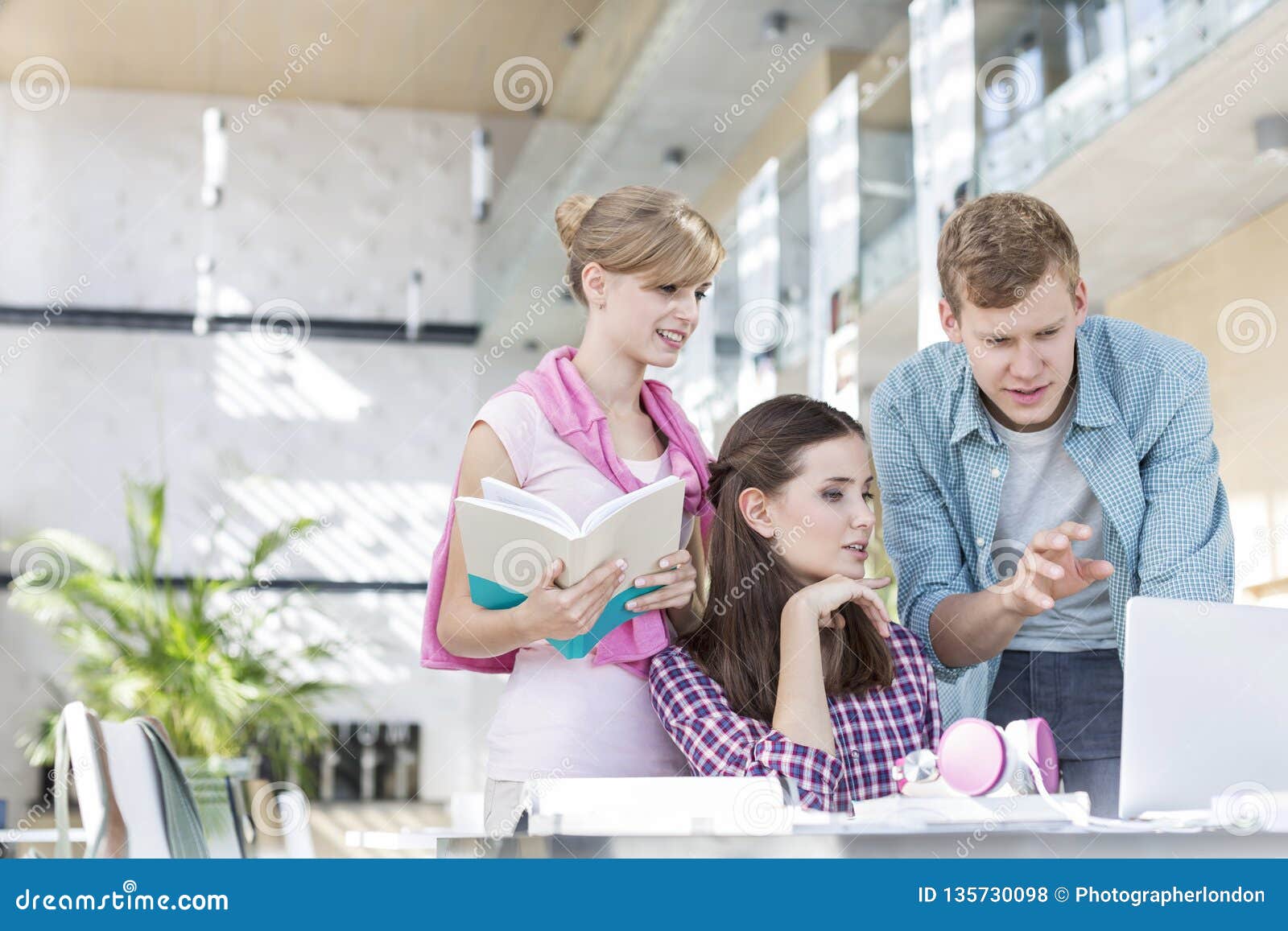 Young Students Discussing Over Laptop while Making Assignment at Table ...