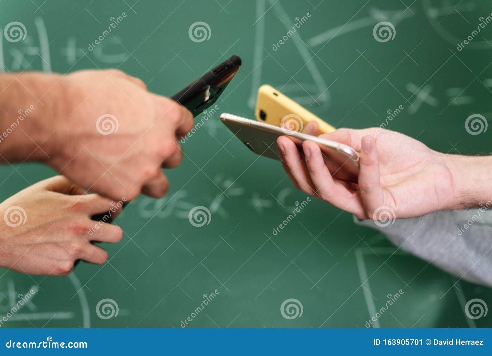Students Using Mobile Phones in Classroom with a Chalkboard in the ...