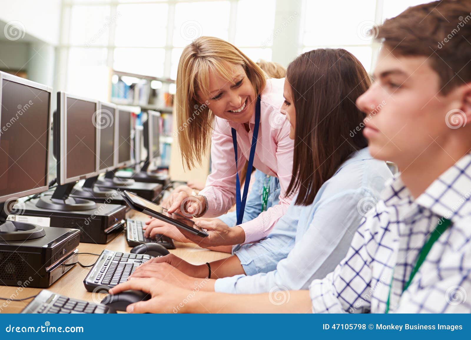Students Working at Computers in Library with Teacher Stock Photo ...