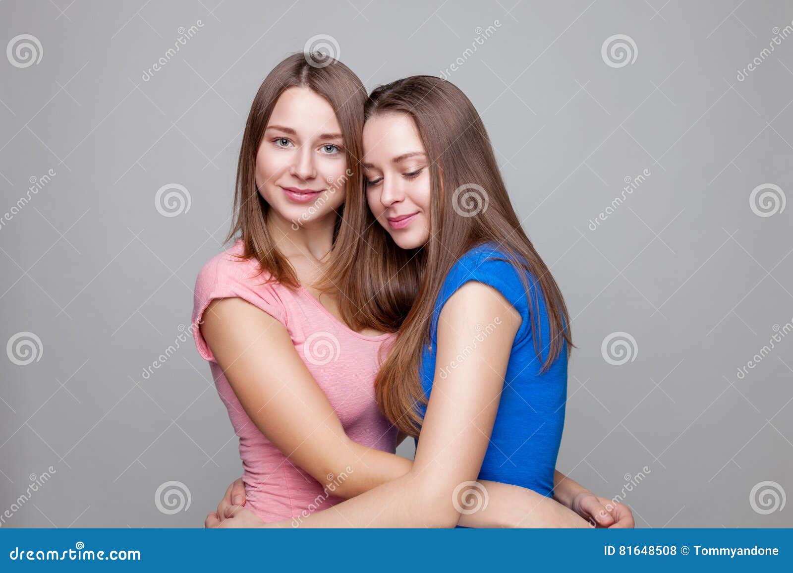 Studio Portait of Young Twin Sisters Embracing Stock Photo - Image of ...