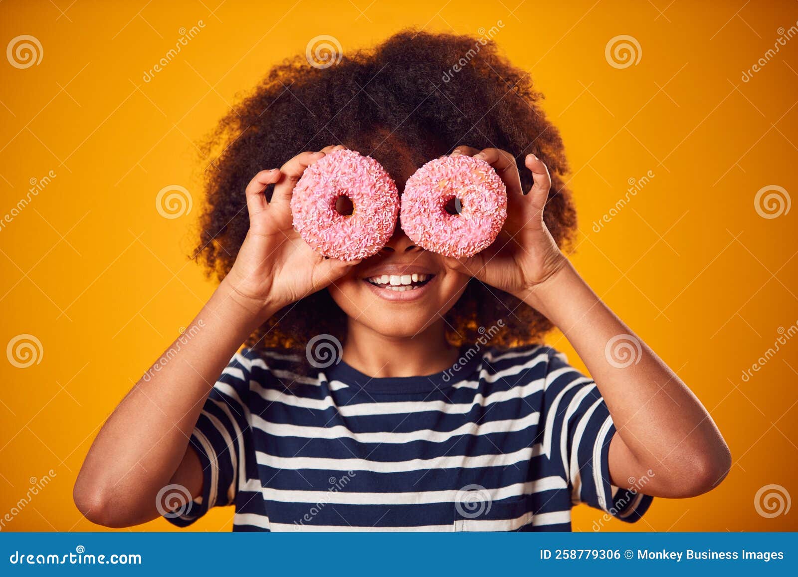 Studio Portrait of Boy Holding Two Donuts in Front of Eyes Against ...