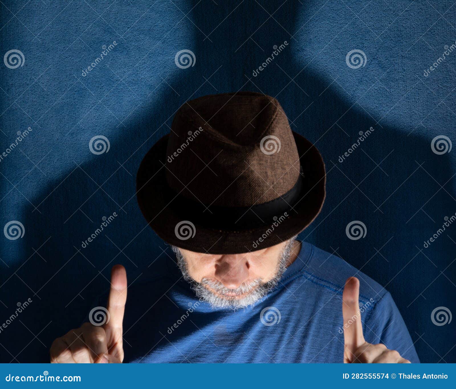 Studio Portrait of Man Wearing Hat with Head Down and Gesticulating ...