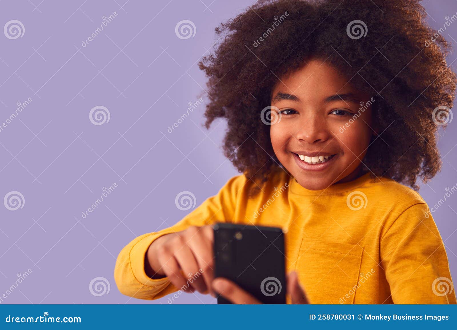 Studio Portrait of Young Boy Using Mobile Phone Against Purple ...