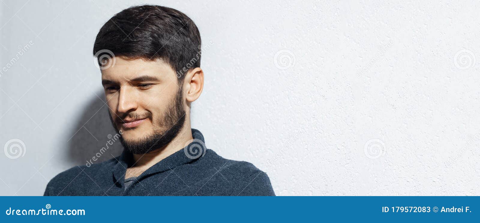 Studio Portrait of Young Guy Looking Down on White Textured Wall ...