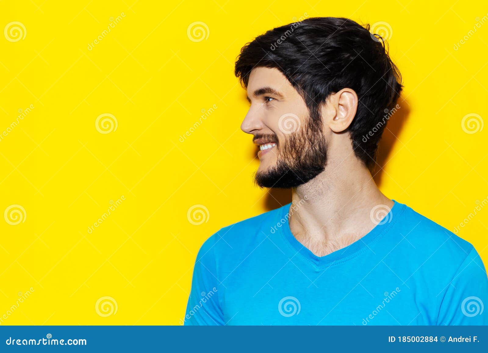 Studio Profile Portrait of Young Smiling Guy in Cyan Shirt Looking on ...