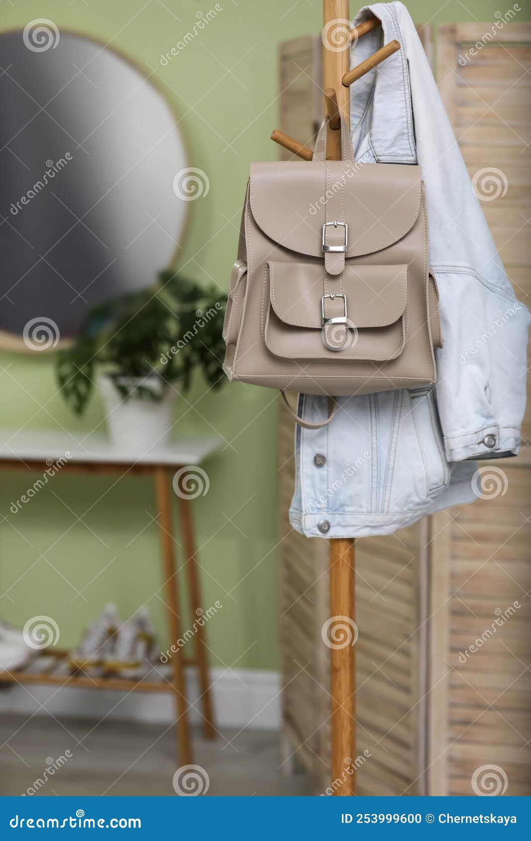 Stylish Beige Backpack and Jacket Hanging on Clothes Rack Indoors Stock ...