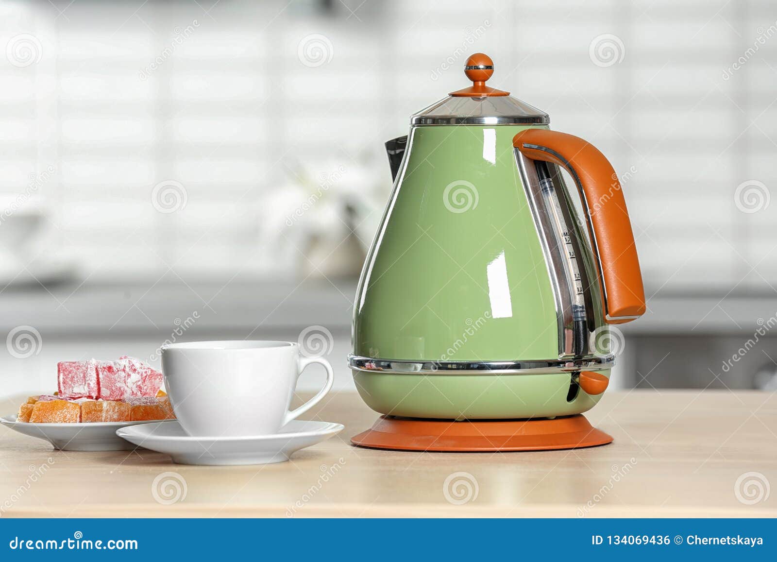 Stylish Electrical Kettle, Cup and Plate with Sweets on Table Against ...
