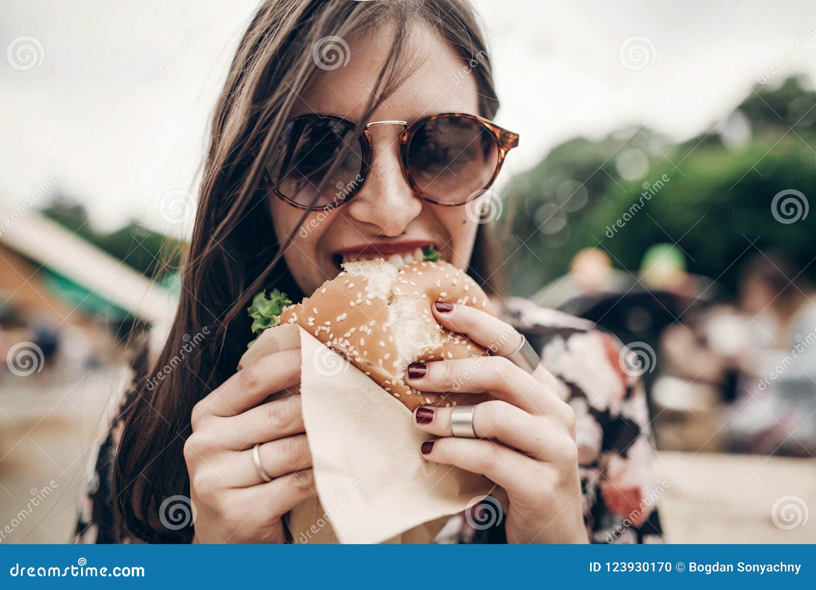 Stylish Hipster Woman Eating Juicy Burger. Boho Girl Biting Yummy ... Stylish Hipster Woman Eating Juicy Burger. Boho Girl Biting Yummy ...