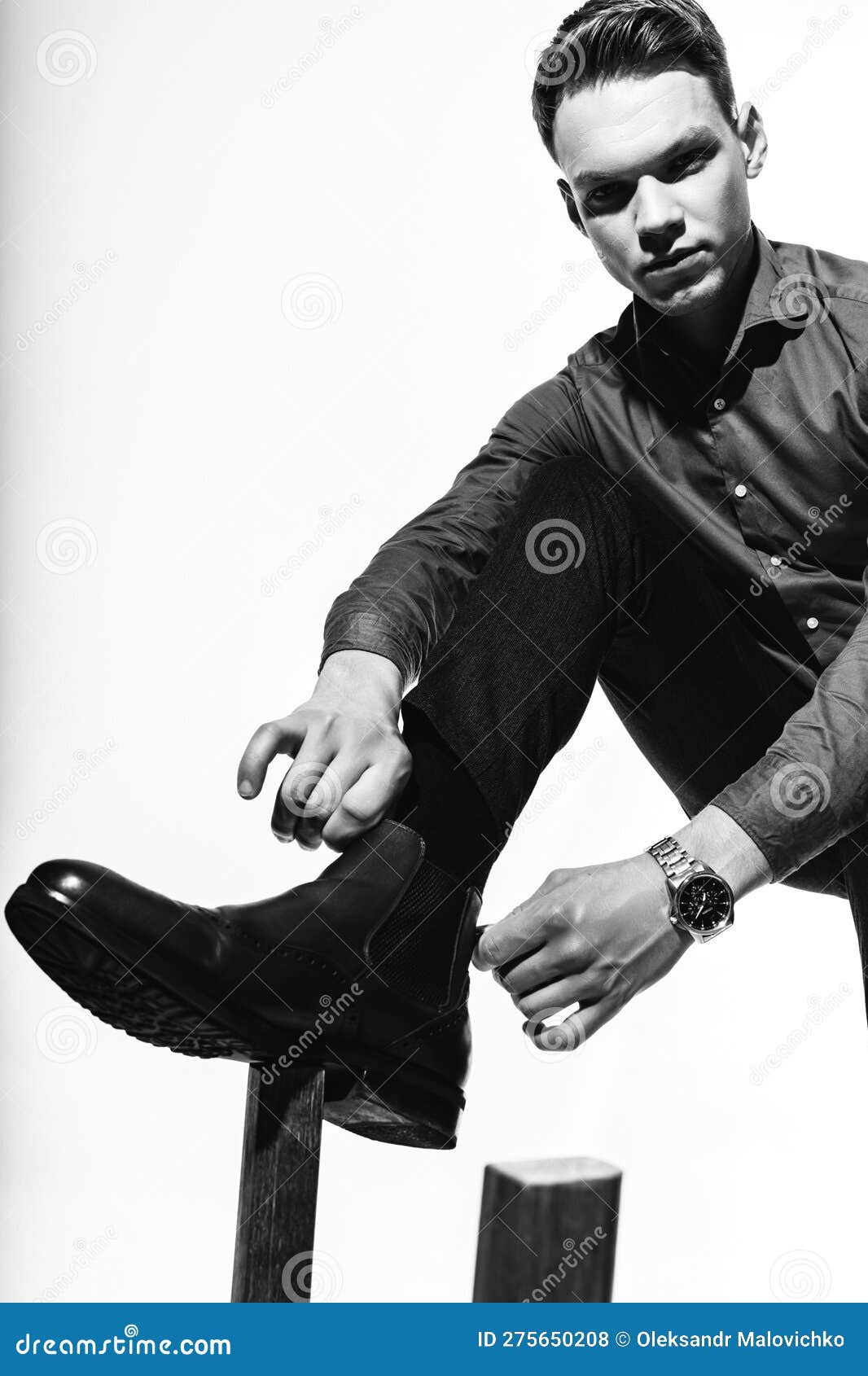 Stylish Man Posing with a Chair in a Photo Studio, Resting His Foot on ... Stylish Man Posing with a Chair in a Photo Studio, Resting His Foot on ...