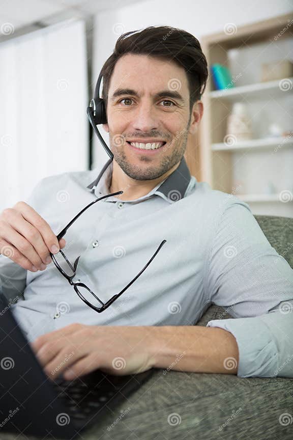 Suave Man Sat on Sofa Using Headset and Laptop Computer Stock Image ...