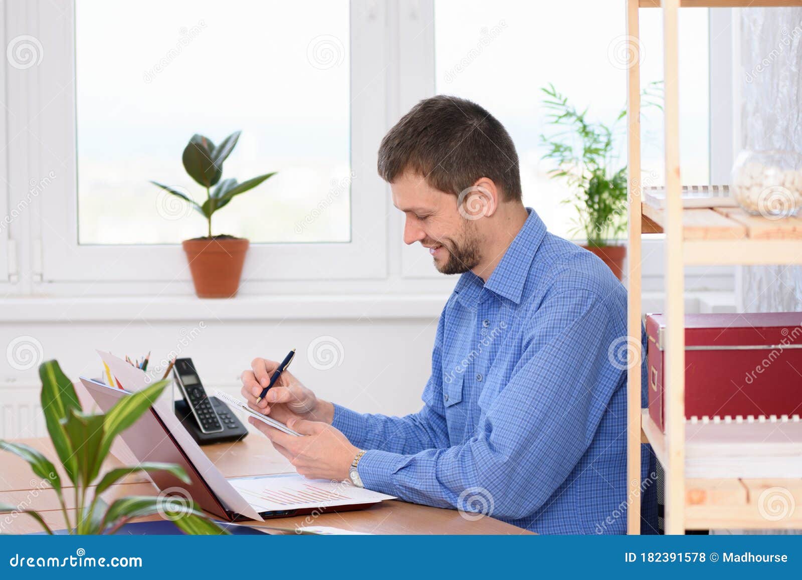 Successful Office Worker with a Smile Makes an Entry in a Notebook ...