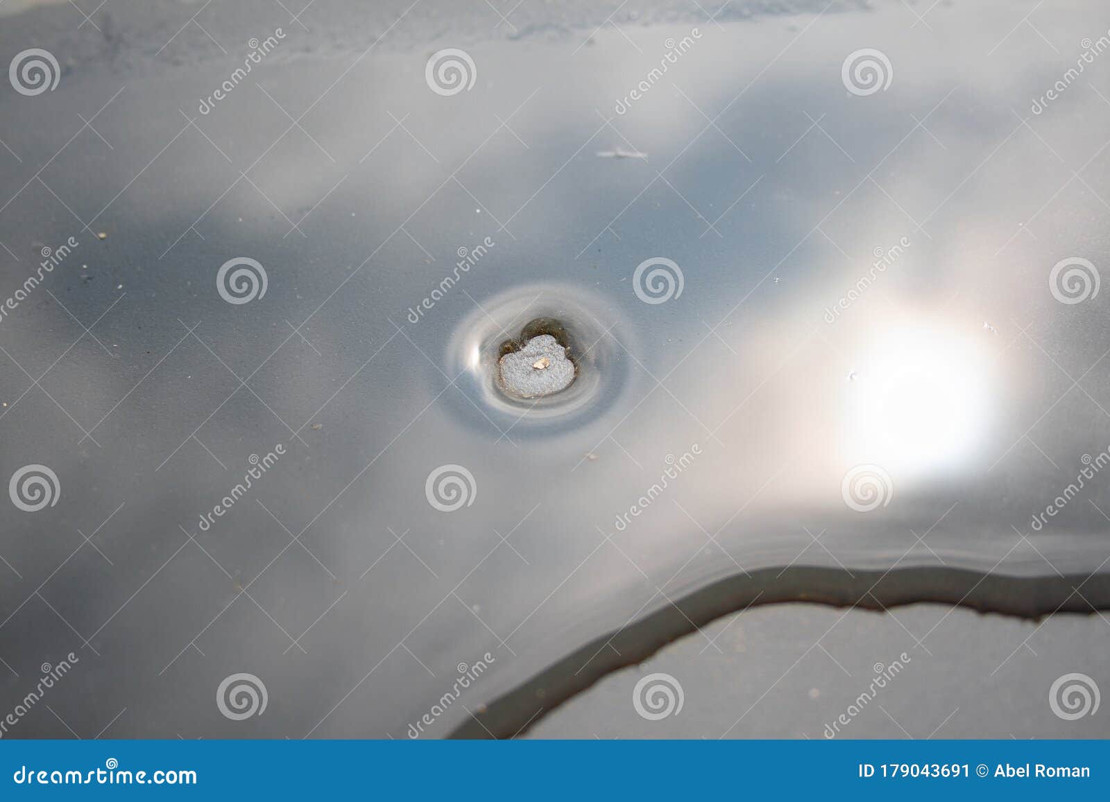 Sun and Clouds Reflected in a Puddle of Water on a Black Background ...