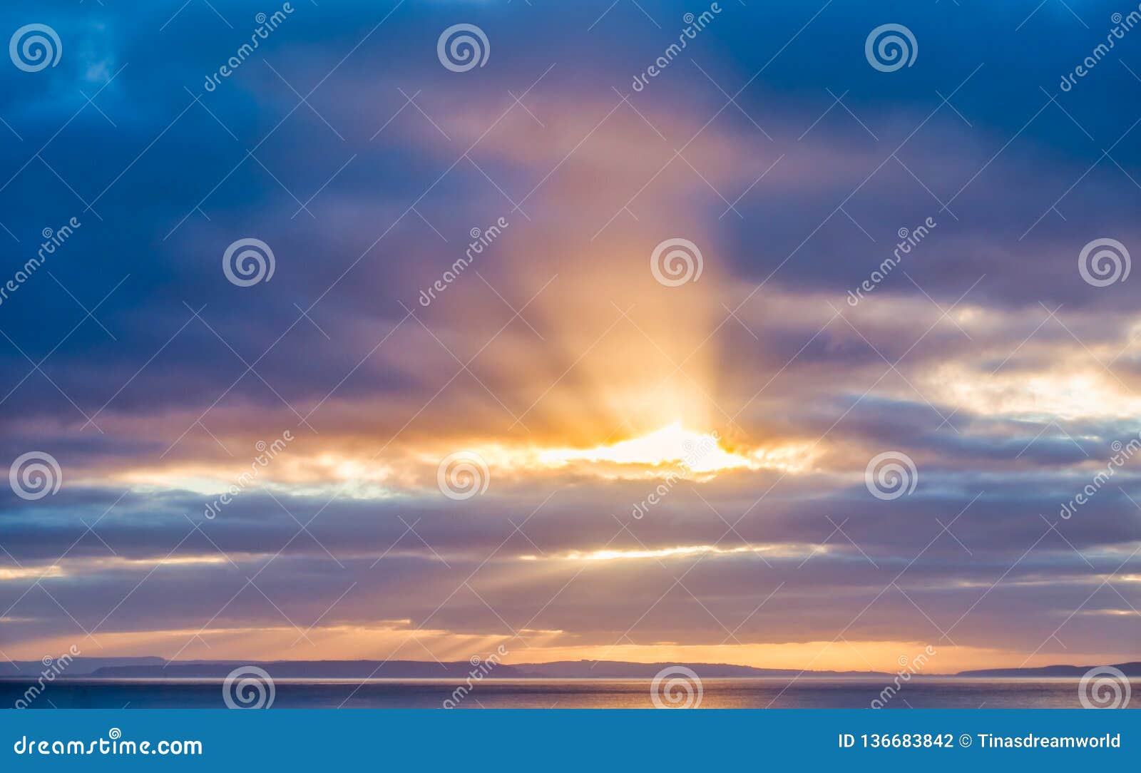 Sun Rays Bursting through Dark Blue Clouds Onto the Sea Stock Photo ...