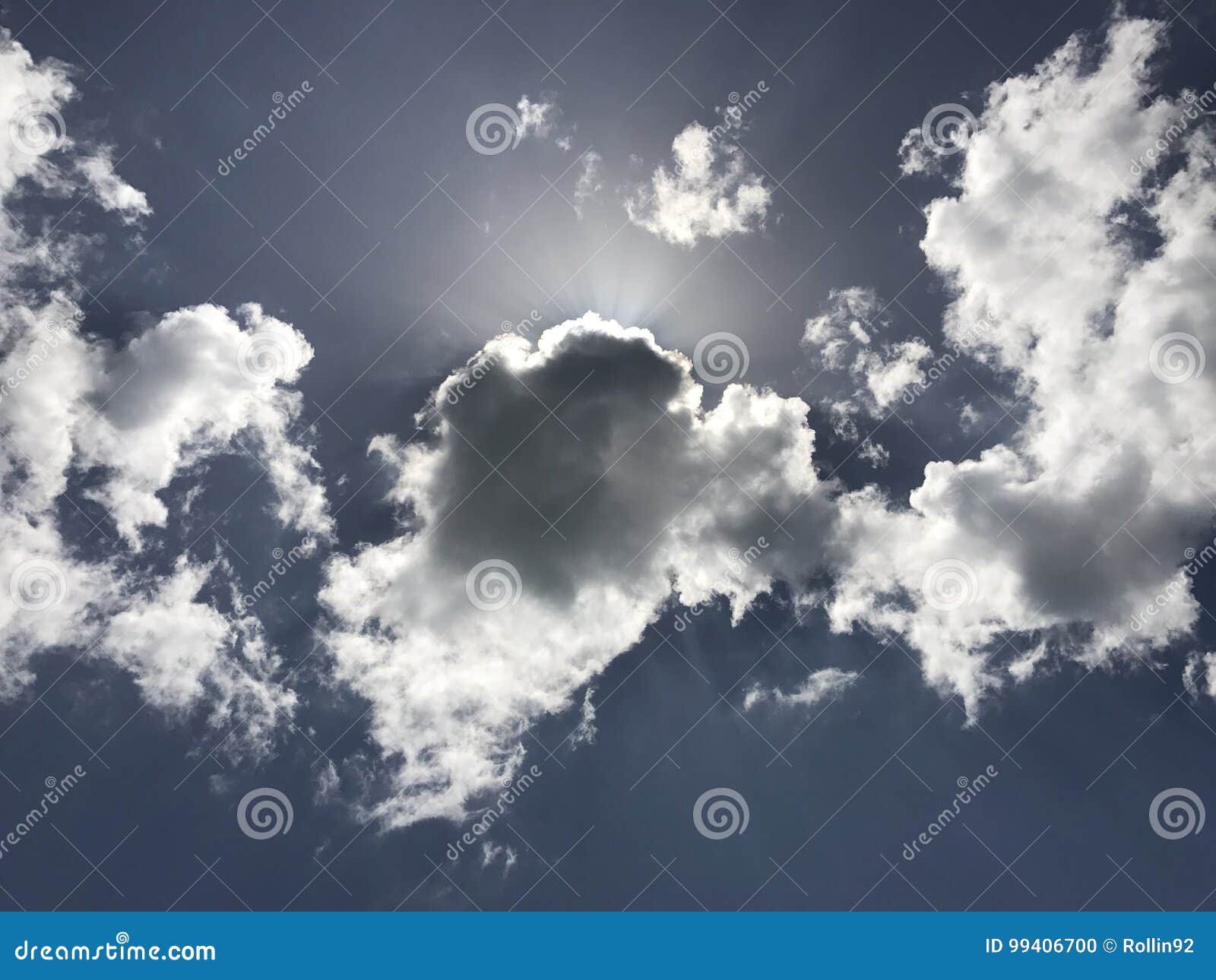 Sun Rays Shine Behind White Clouds Stock Photo - Image of clouds, blue ...