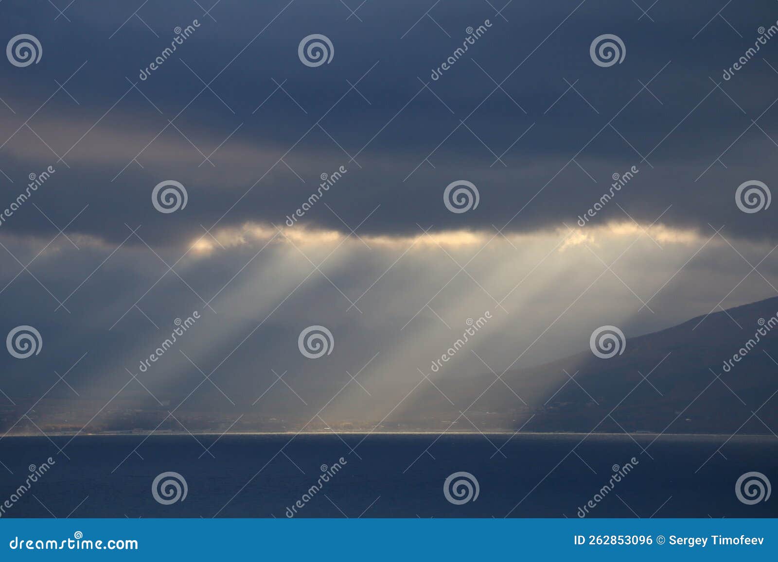 The Sun Rays Shine through the Clouds on the Sea Surface Stock Photo ...