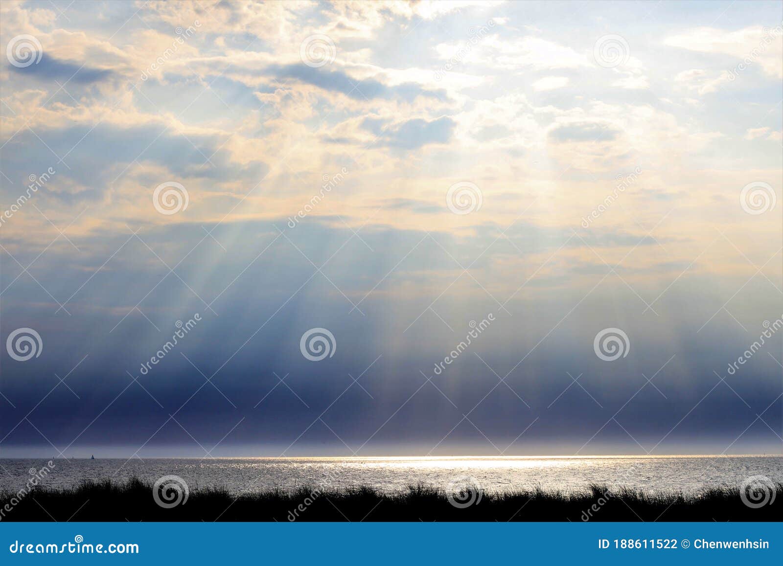 The Sun Behind the Clouds with Rays of Light Shining Down on Sea. Stock ...