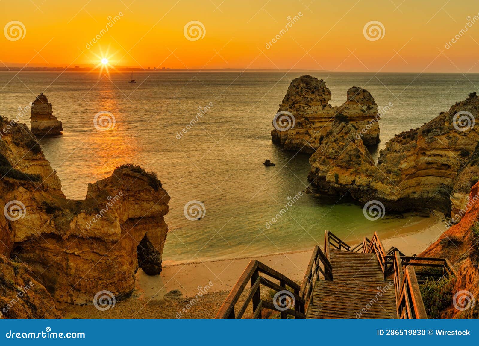 The Sun Sets Behind Two Rocky Cliffs at the Coast with a Dock on it ...