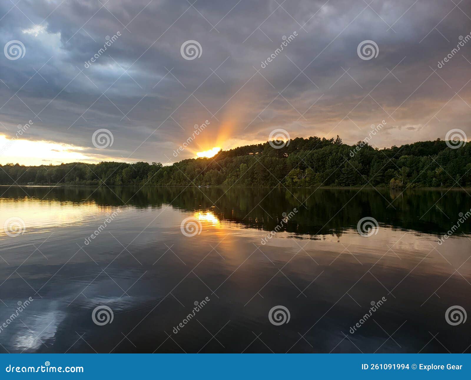 Sun Setting Behind Trees with Reflections Across a Lake Stock Photo ...