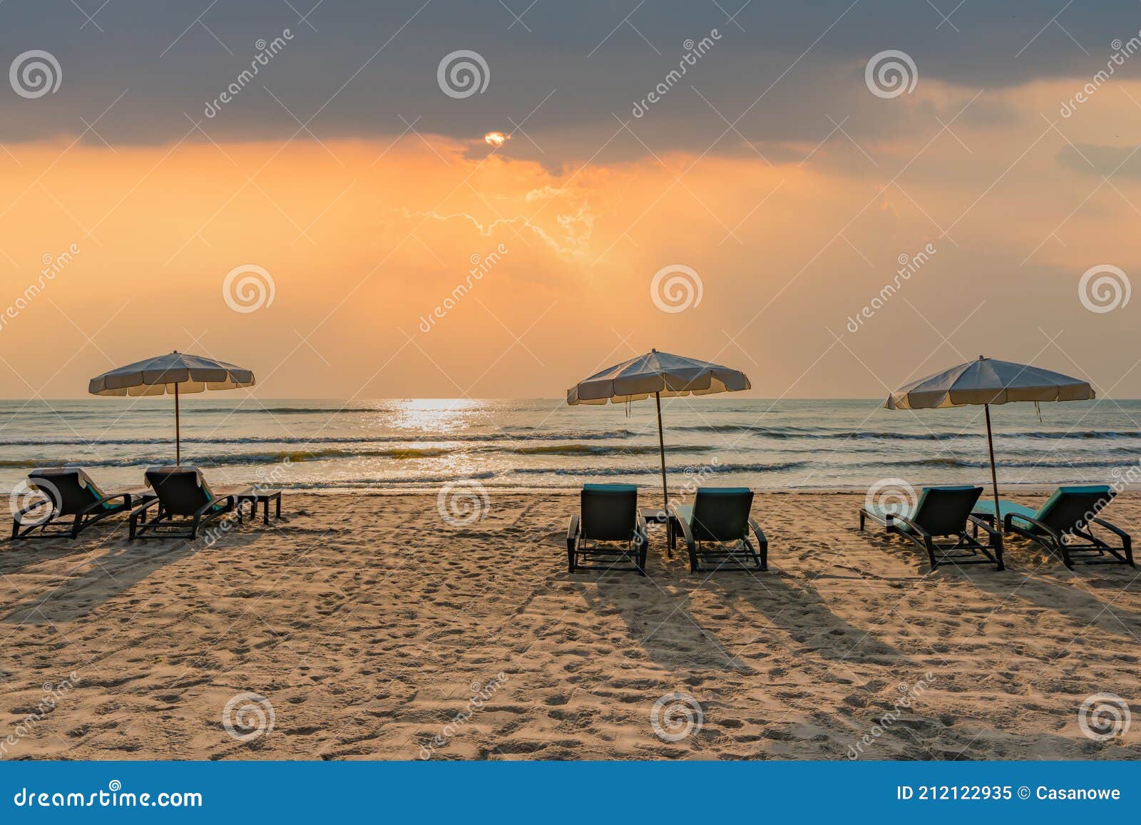 Sun Umbrellas And Chairs On Tropical Beach With Sunset Stock Image