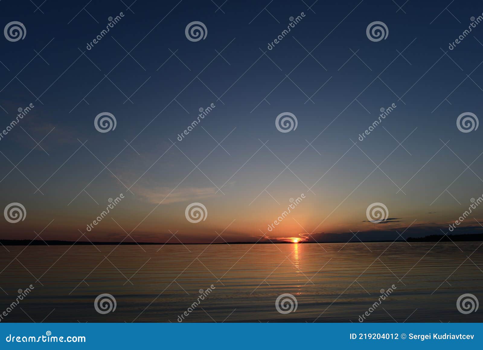 Sunbeam at Sunset from Clouds on the Horizon Above the Lake Water Stock ...