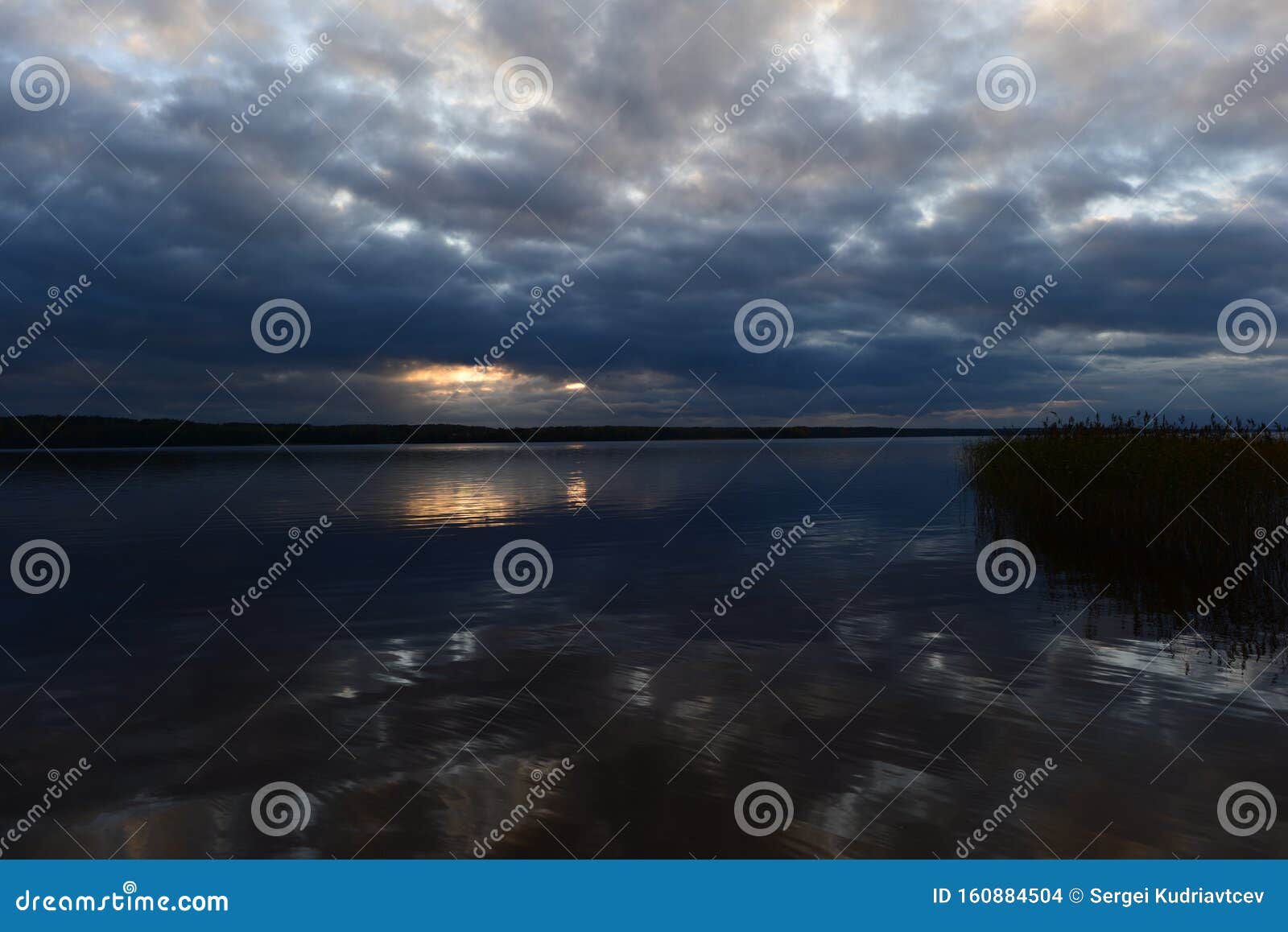 Sunlight from Dark Clouds at Sunset Reflects on the Lake Water Stock ...