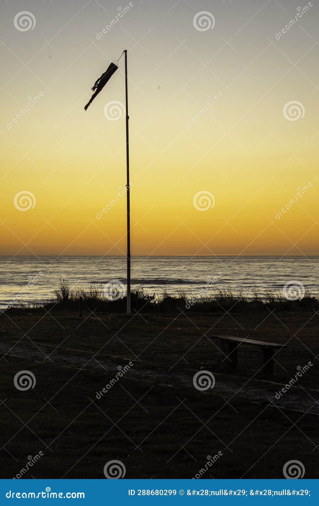 Sunset at the Beach with a Windsock Silhouetted by the Setting Sun ...