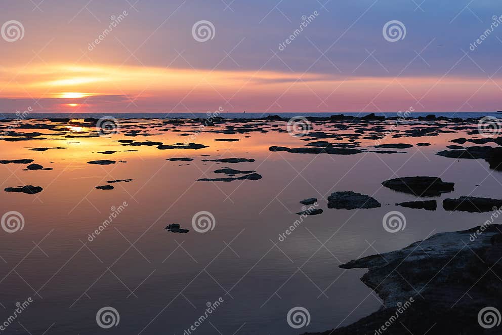 Sunset Reflected on the Sea As in a Mirror with Rocks Emerging on the Surface of the Water Stock ...