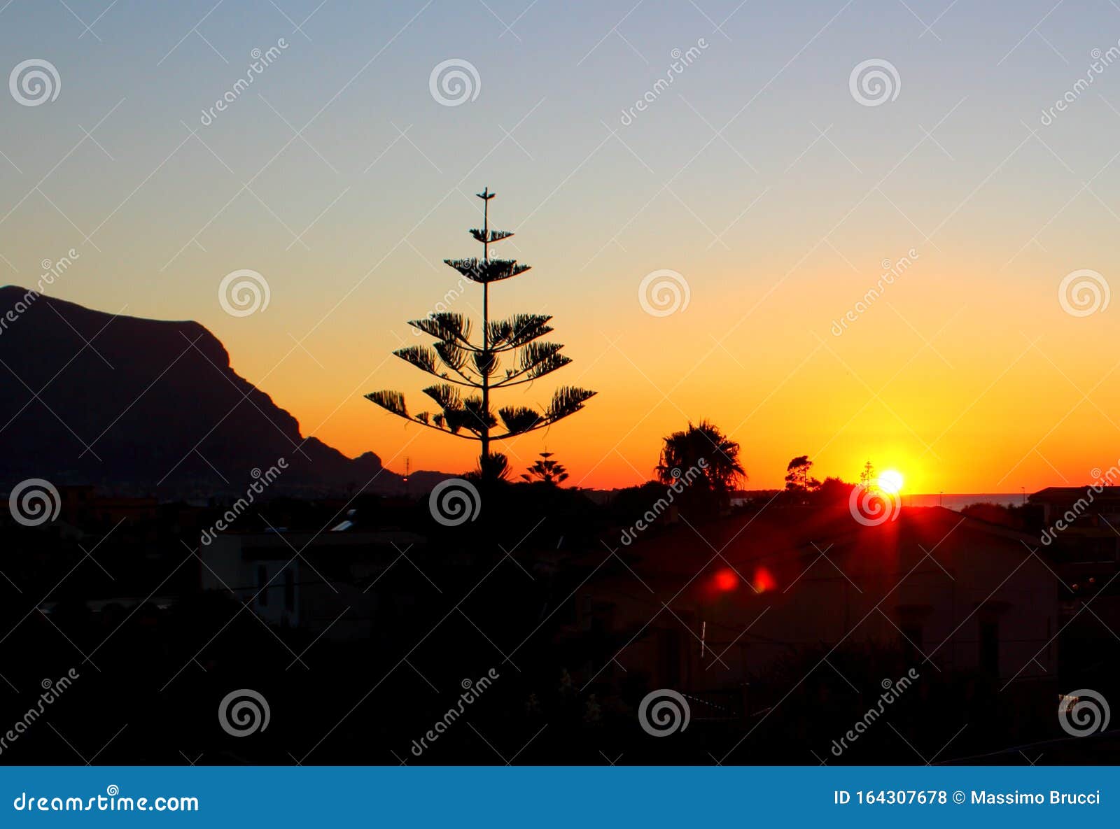 Sunset with Silhouette of Promontory in the Background and Trees in the ...
