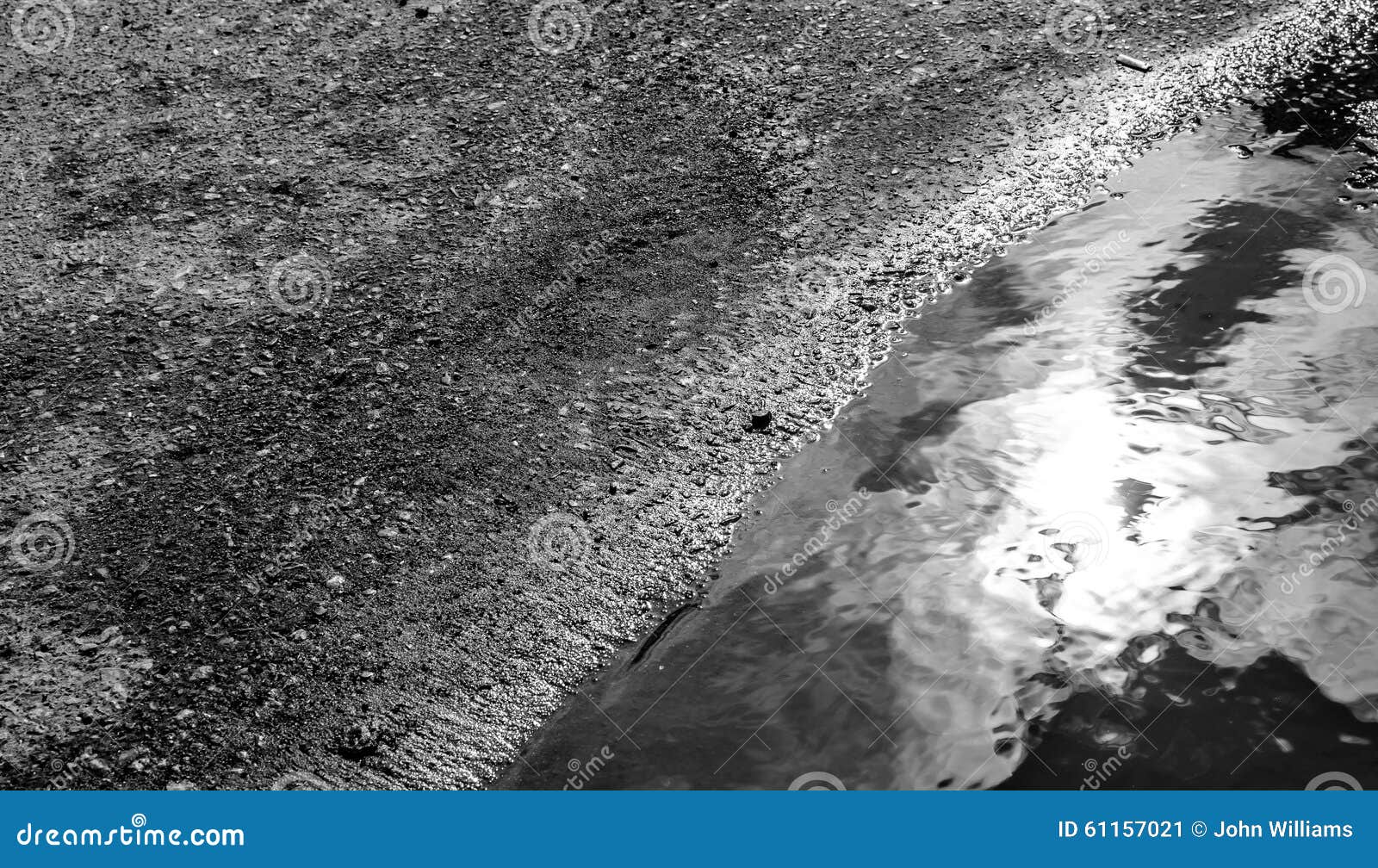 Sunshine Reflecting from a Puddle of Rain Water in a Road Stock Image ...