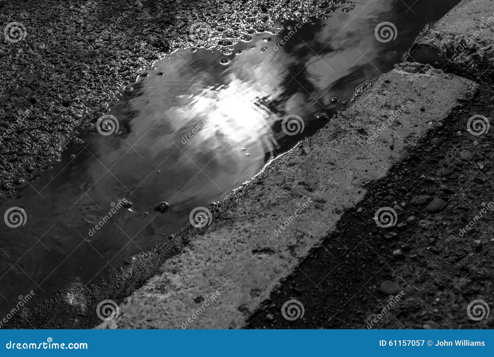 Sunshine Reflecting from a Puddle of Rain Water in a Road Stock Image ...